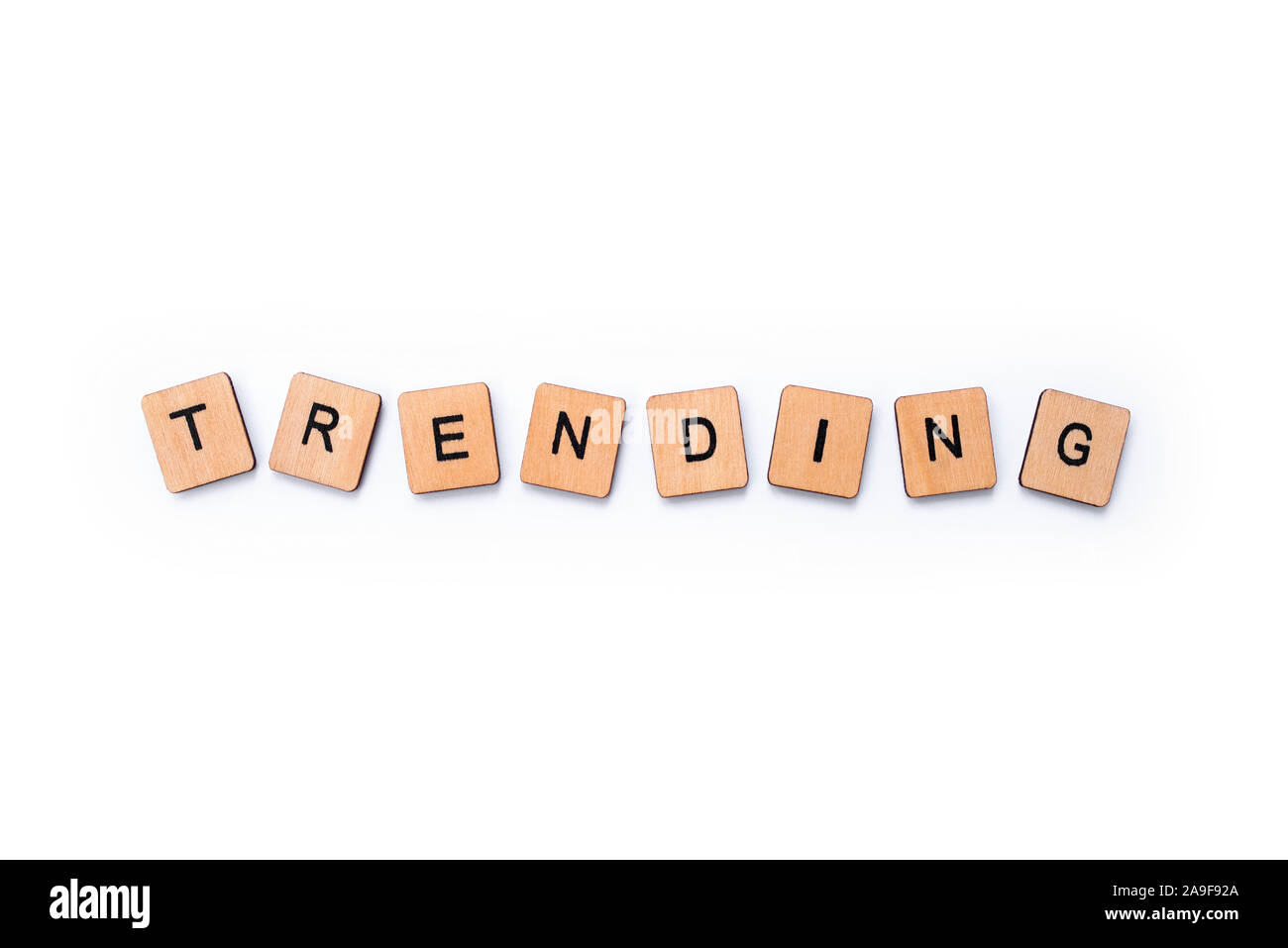 The word TRENDING, spelt with wooden letter tiles over a white ...