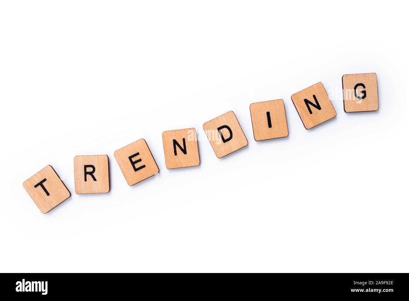 The word TRENDING, spelt with wooden letter tiles over a white ...