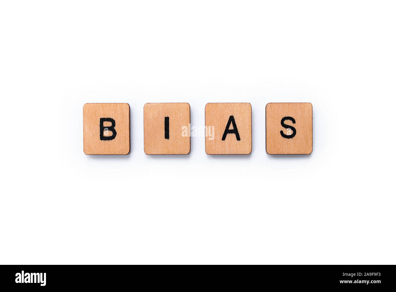 The word BIAS, spelt with wooden letter tiles over a white background ...