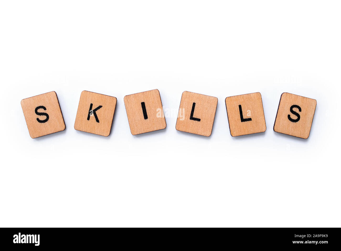 The word SKILLS, spelt with wooden letter tiles over a white background ...