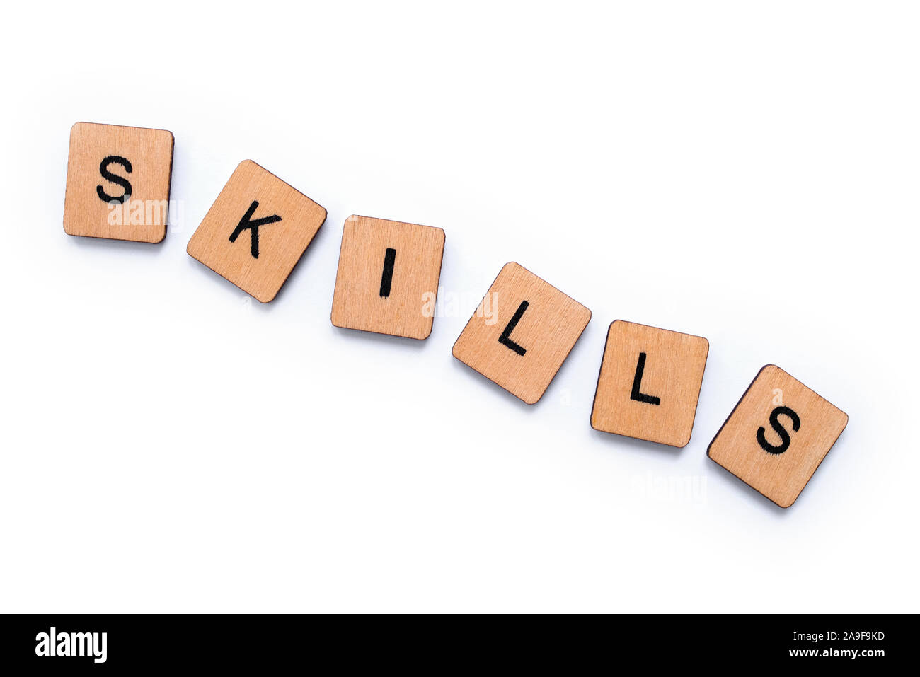 The word SKILLS, spelt with wooden letter tiles over a white background ...
