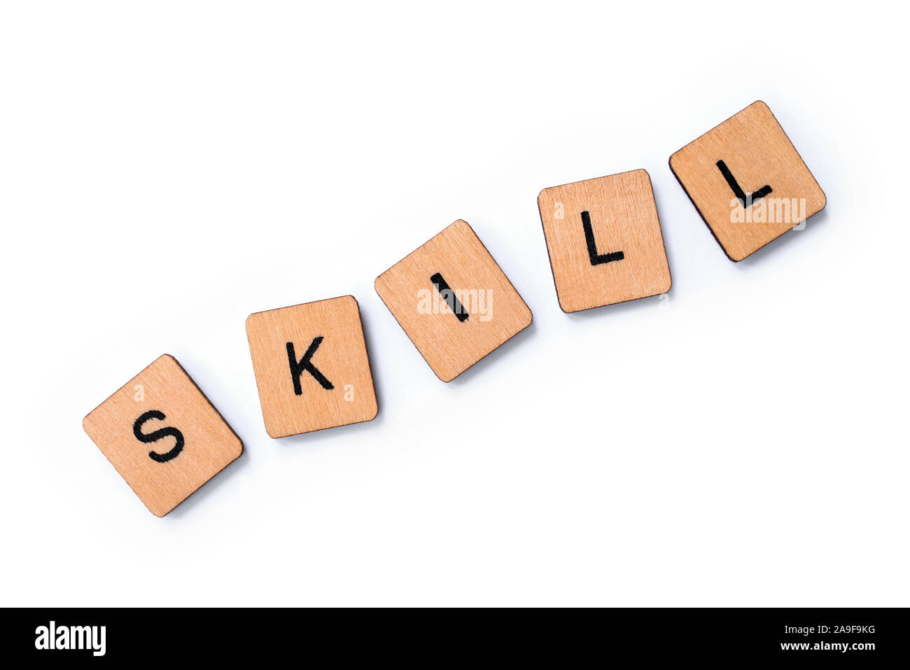 The word SKILL, spelt with wooden letter tiles over a white background ...