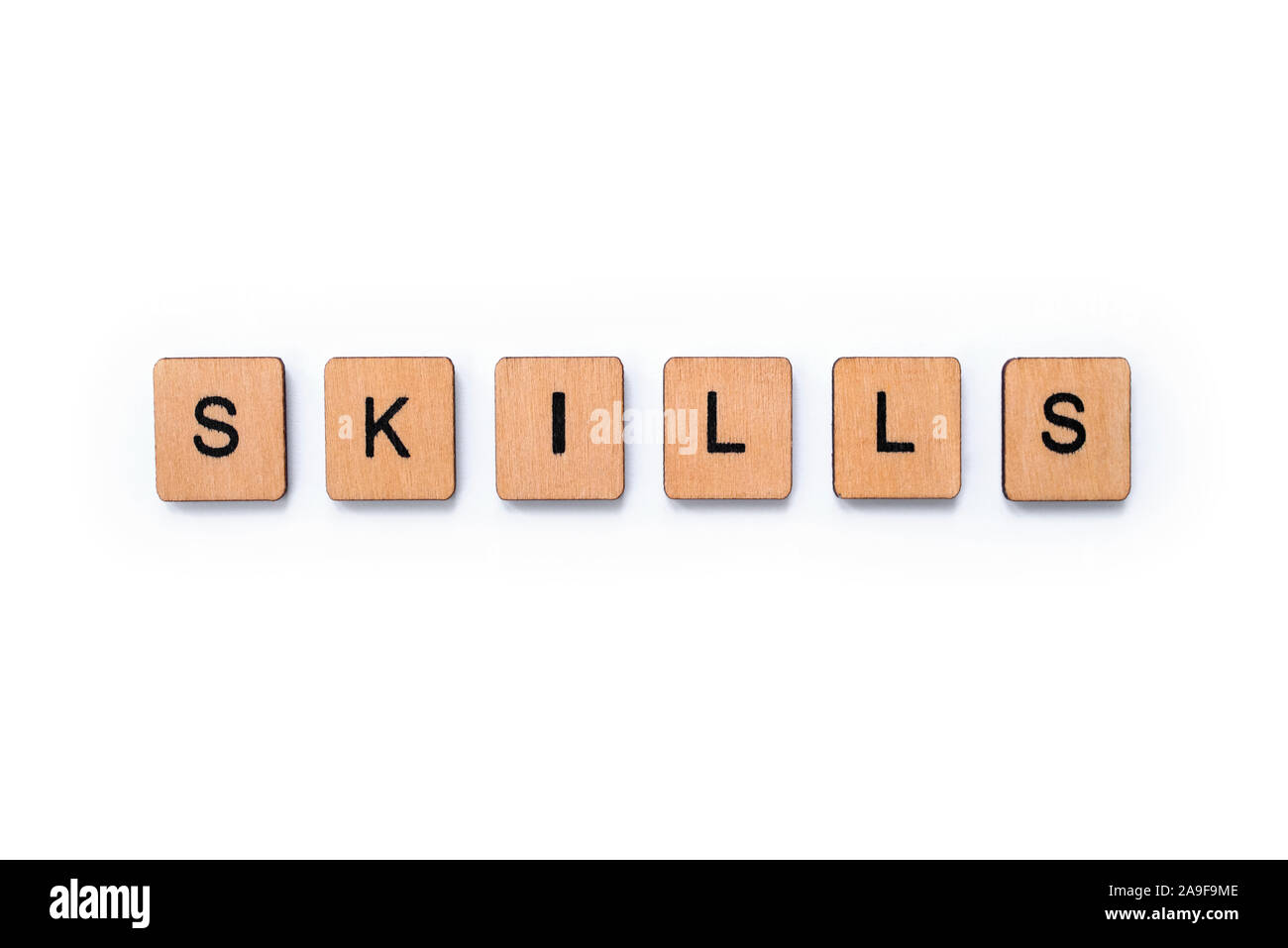 The word SKILLS, spelt with wooden letter tiles over a white background ...