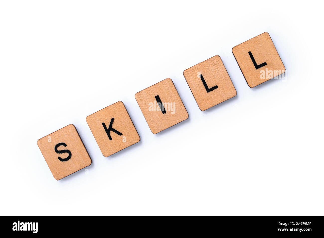 The word SKILL, spelt with wooden letter tiles over a white background ...