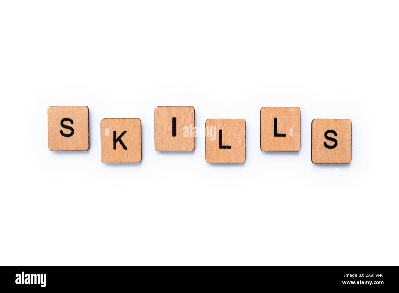 The word SKILLS, spelt with wooden letter tiles over a white background ...