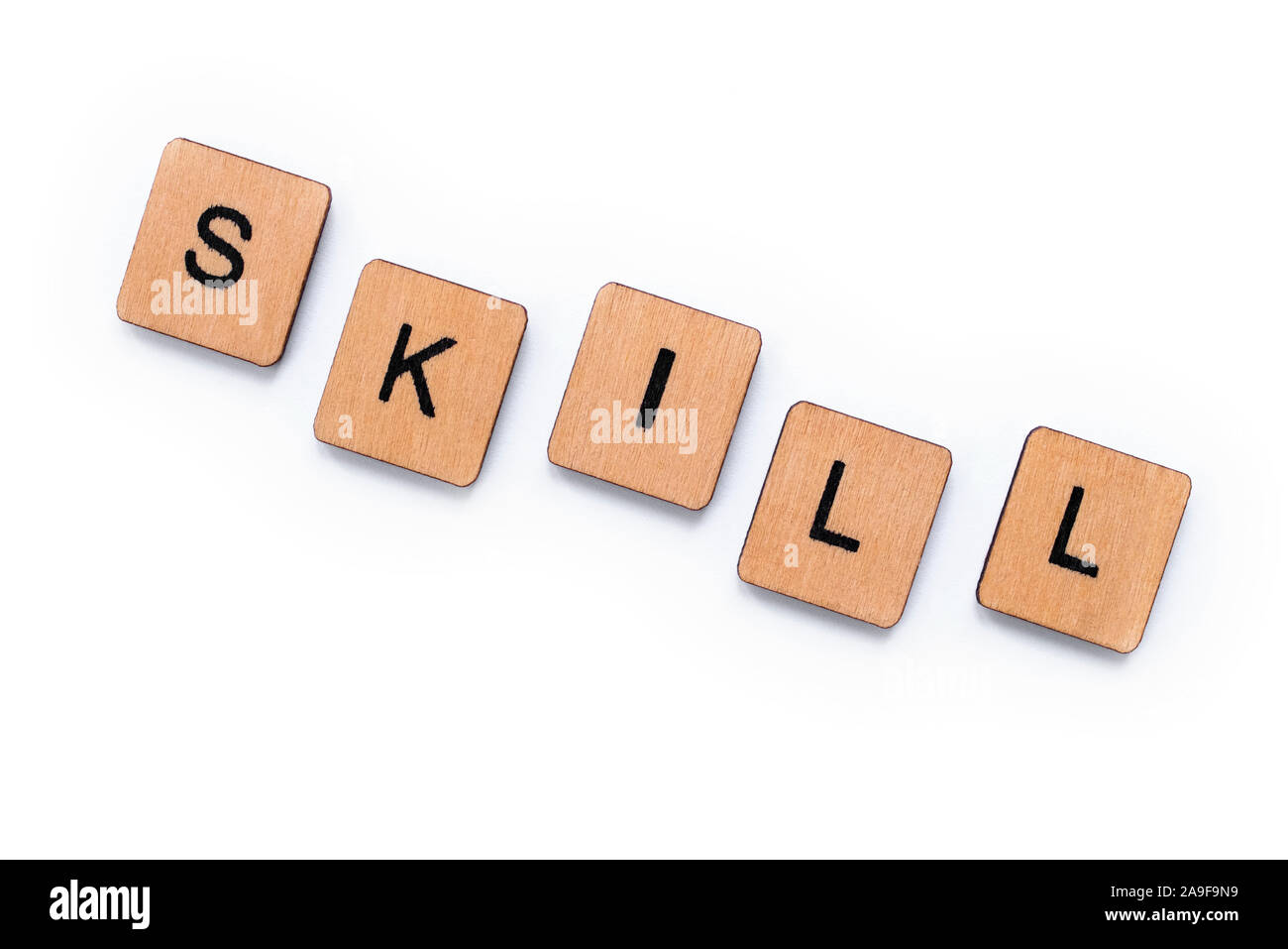 The word SKILL, spelt with wooden letter tiles over a white background ...