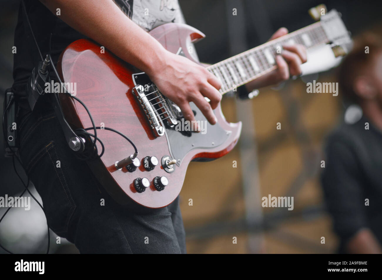 A skilled rock musician in jeans and a t-shirt performs on stage ...