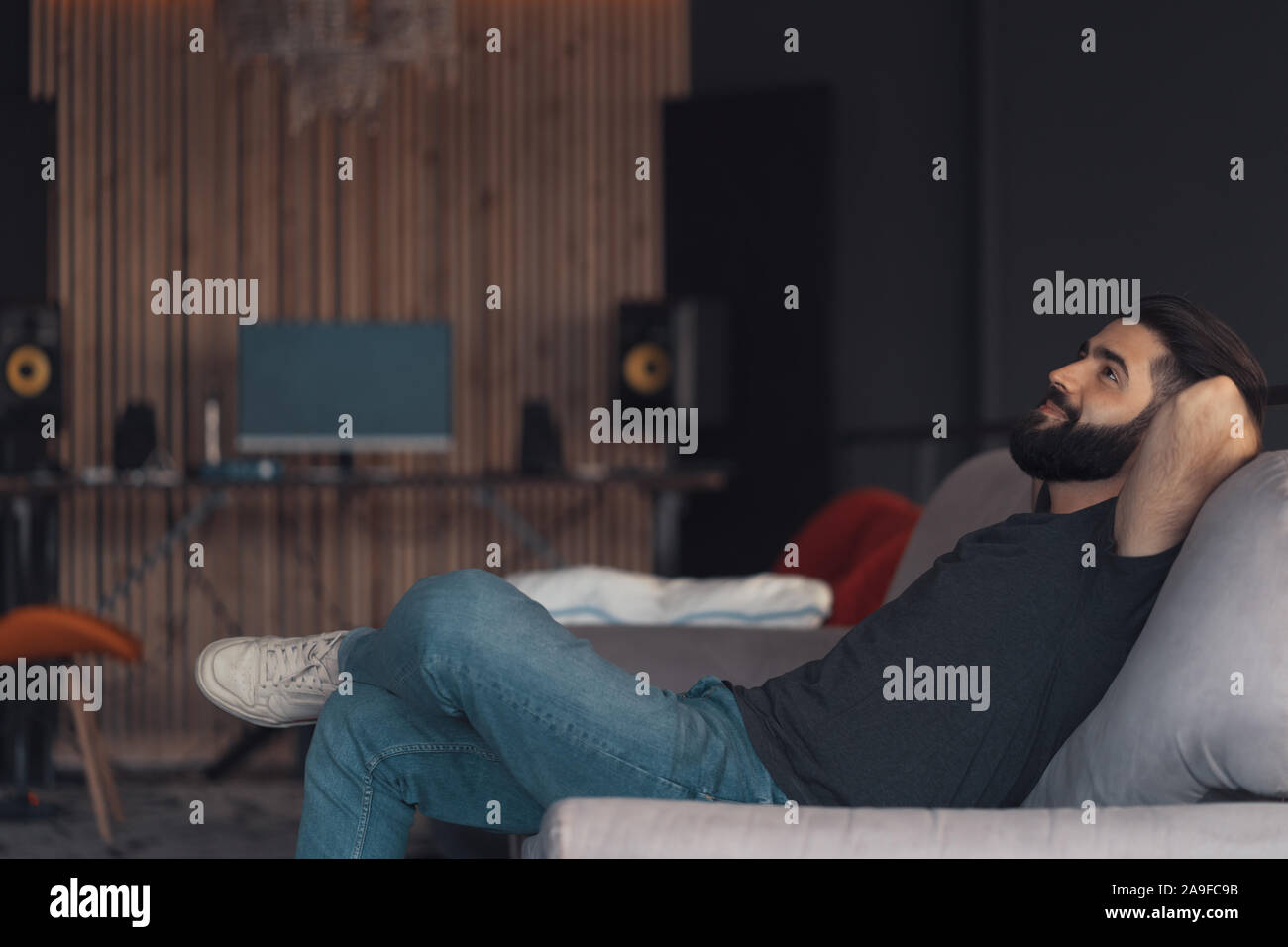 Young attractive guy sitting relaxing on a sofa in his loft office ...