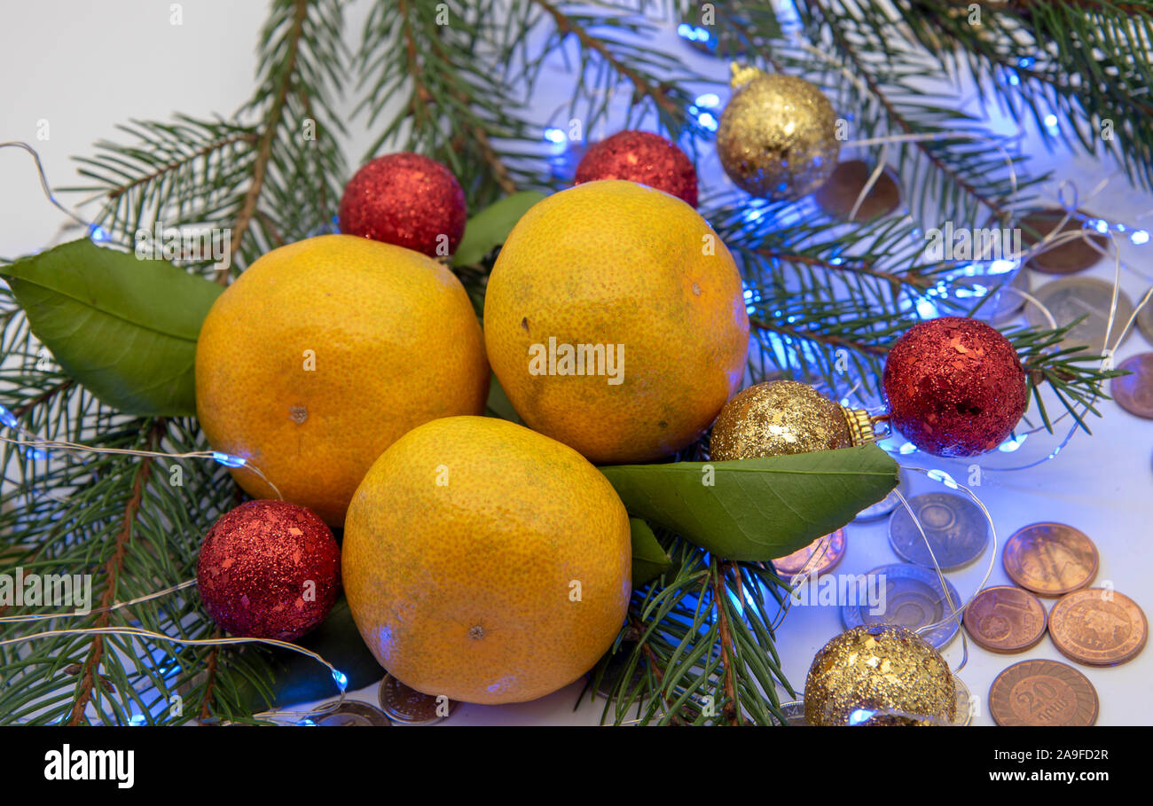 Tangerines, Christmas decorations and coins of different countries lie ...