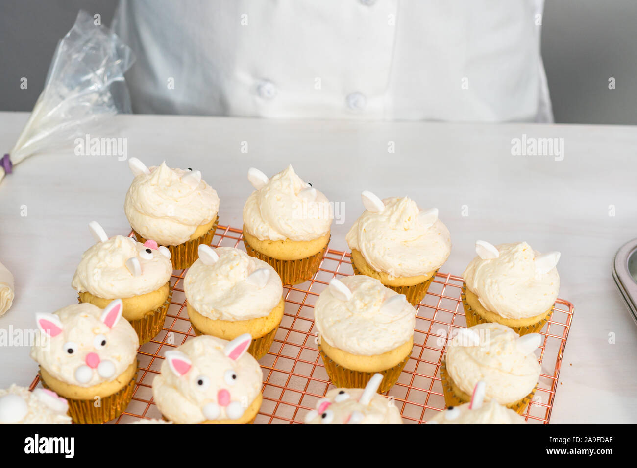 Decorating vanilla cupcakes with a white buttercream icing and bunny ...