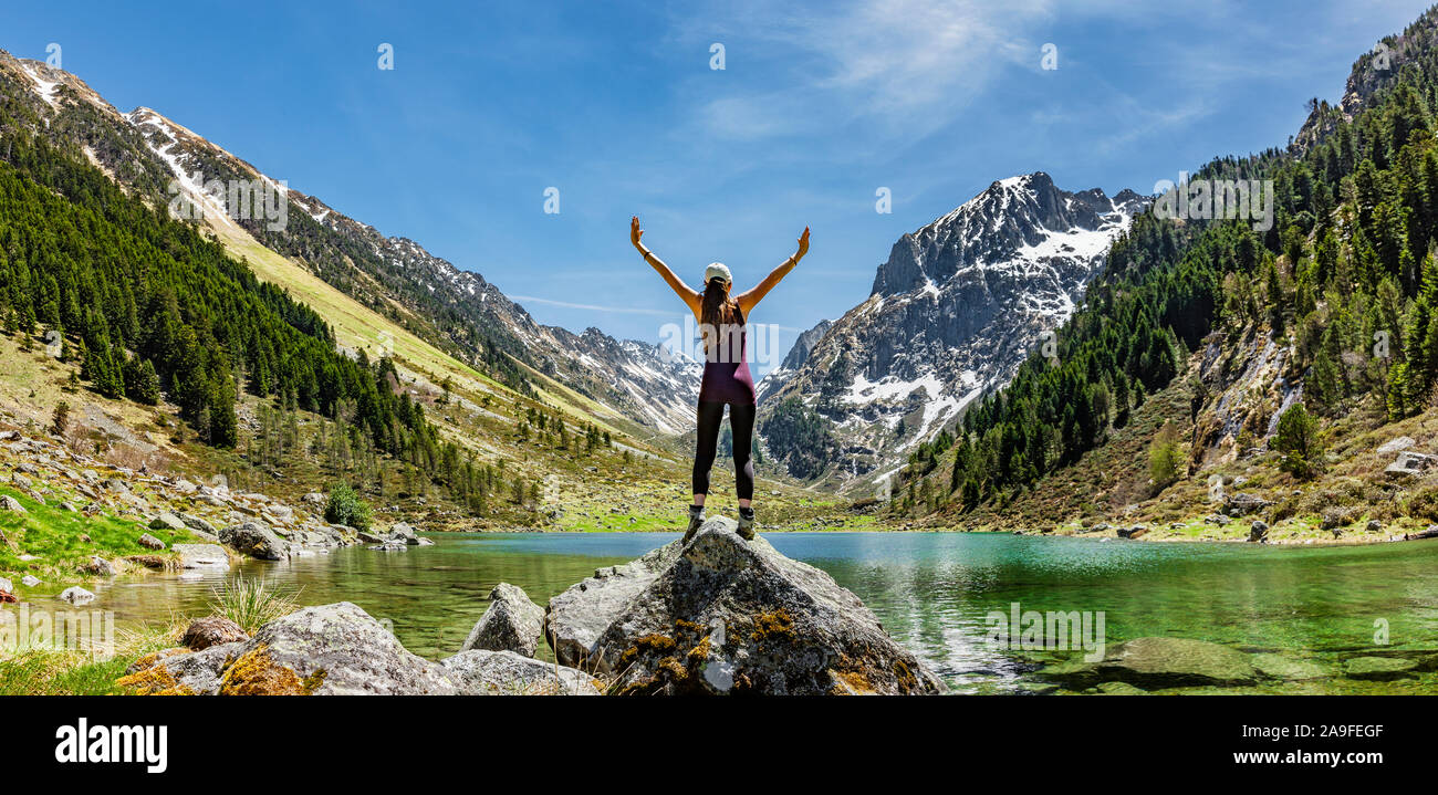Woman in winner pose on a rock at a lake in the mountains Stock Photo ...