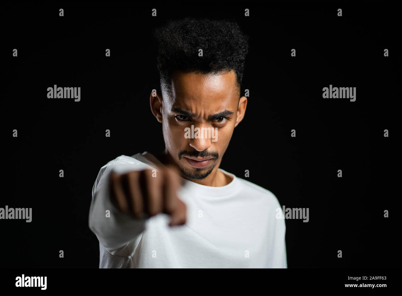 Young serious handsome african man with closed fist pointing to camera ...