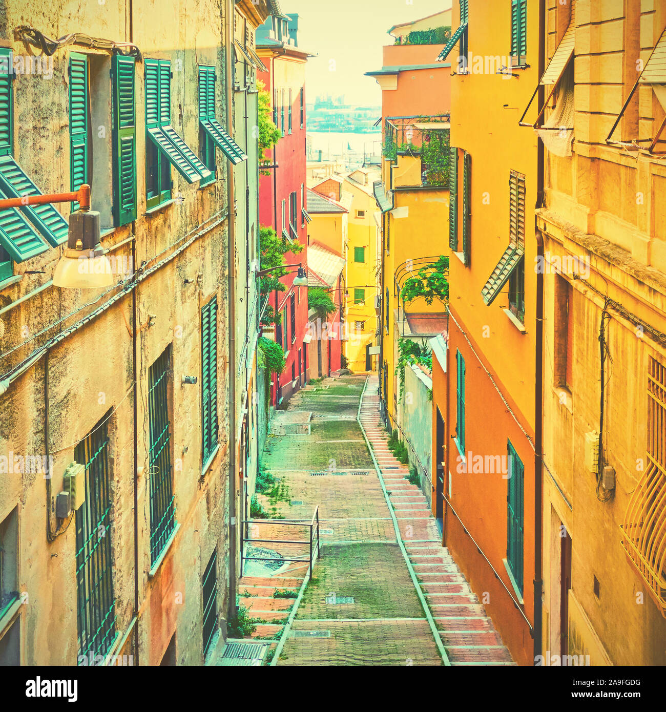 Perspective of old downhill street in Genoa, Italy. Vintage style toned ...