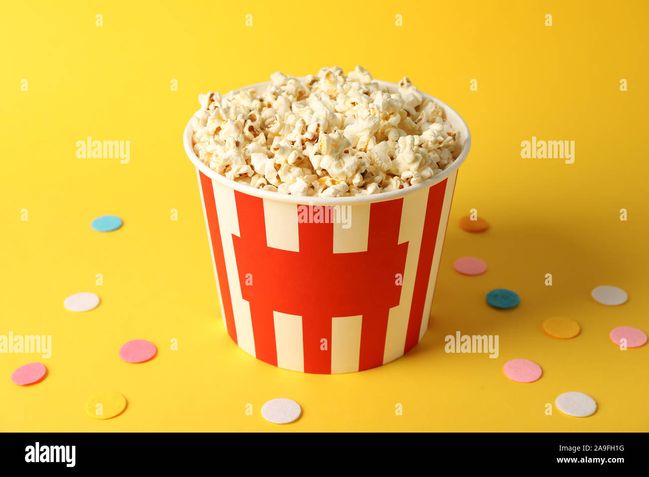 Confetti and bucket with popcorn on yellow background, copy space Stock ...