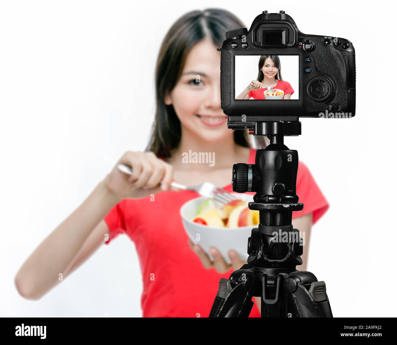 Asian food vlogger with fruit salad behind camera, social media ...