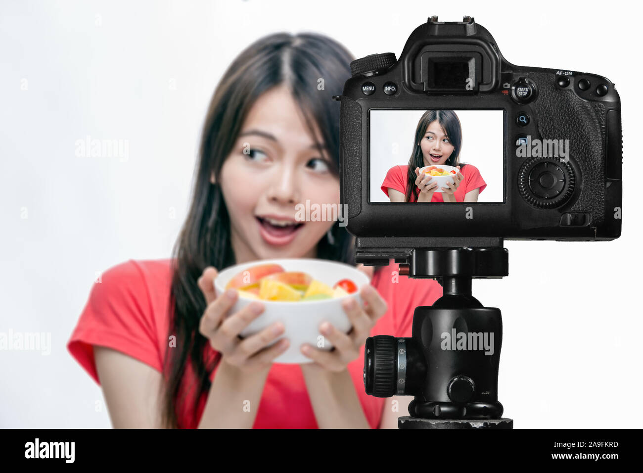 Asian food vlogger with fruit salad behind camera, social media ...
