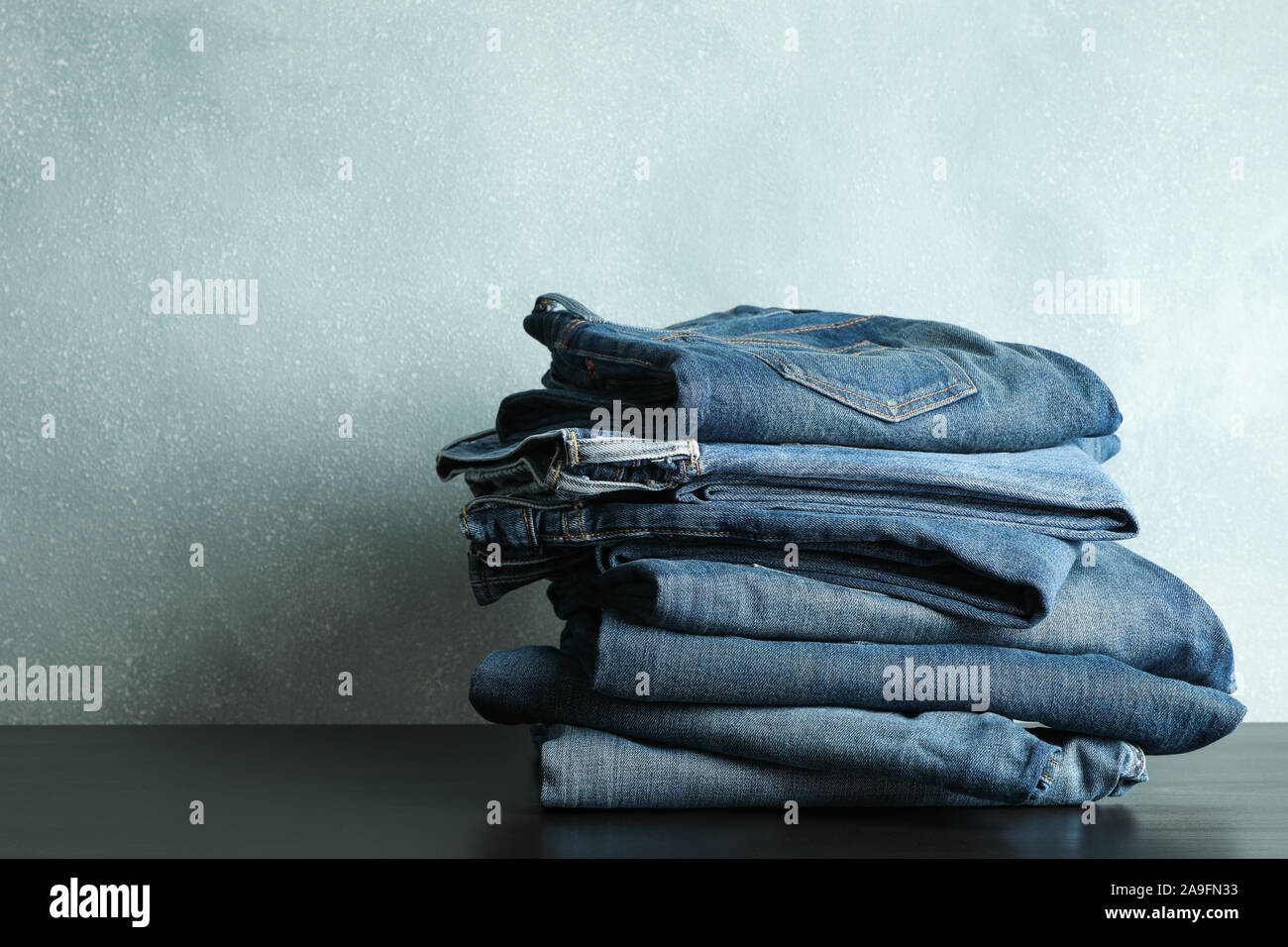 Stack of jeans pants on black table, space for text Stock Photo - Alamy