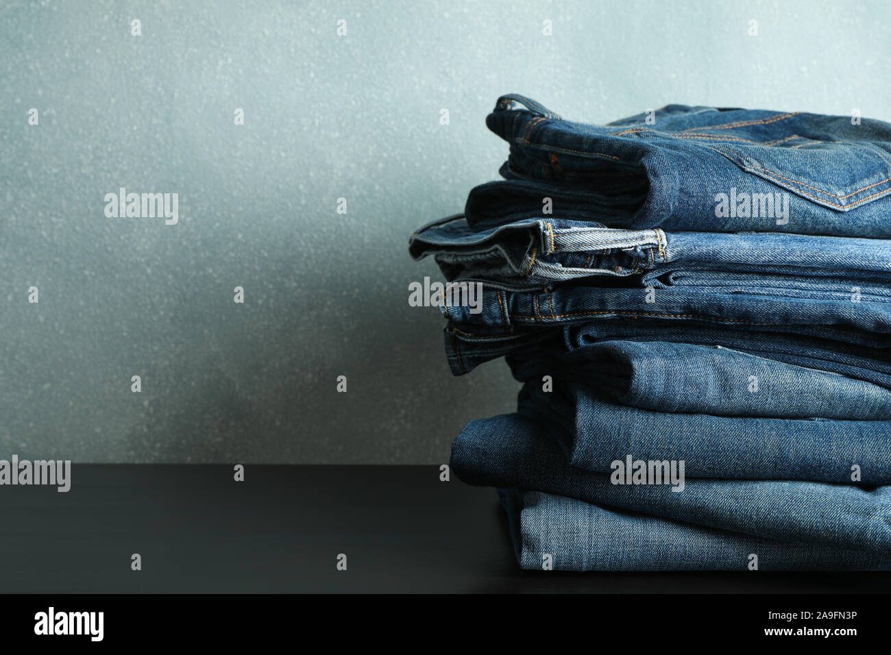 Stack of jeans pants on black table, space for text Stock Photo - Alamy