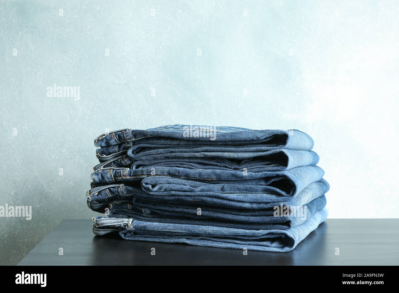 Stack of jeans pants on black table, space for text Stock Photo - Alamy