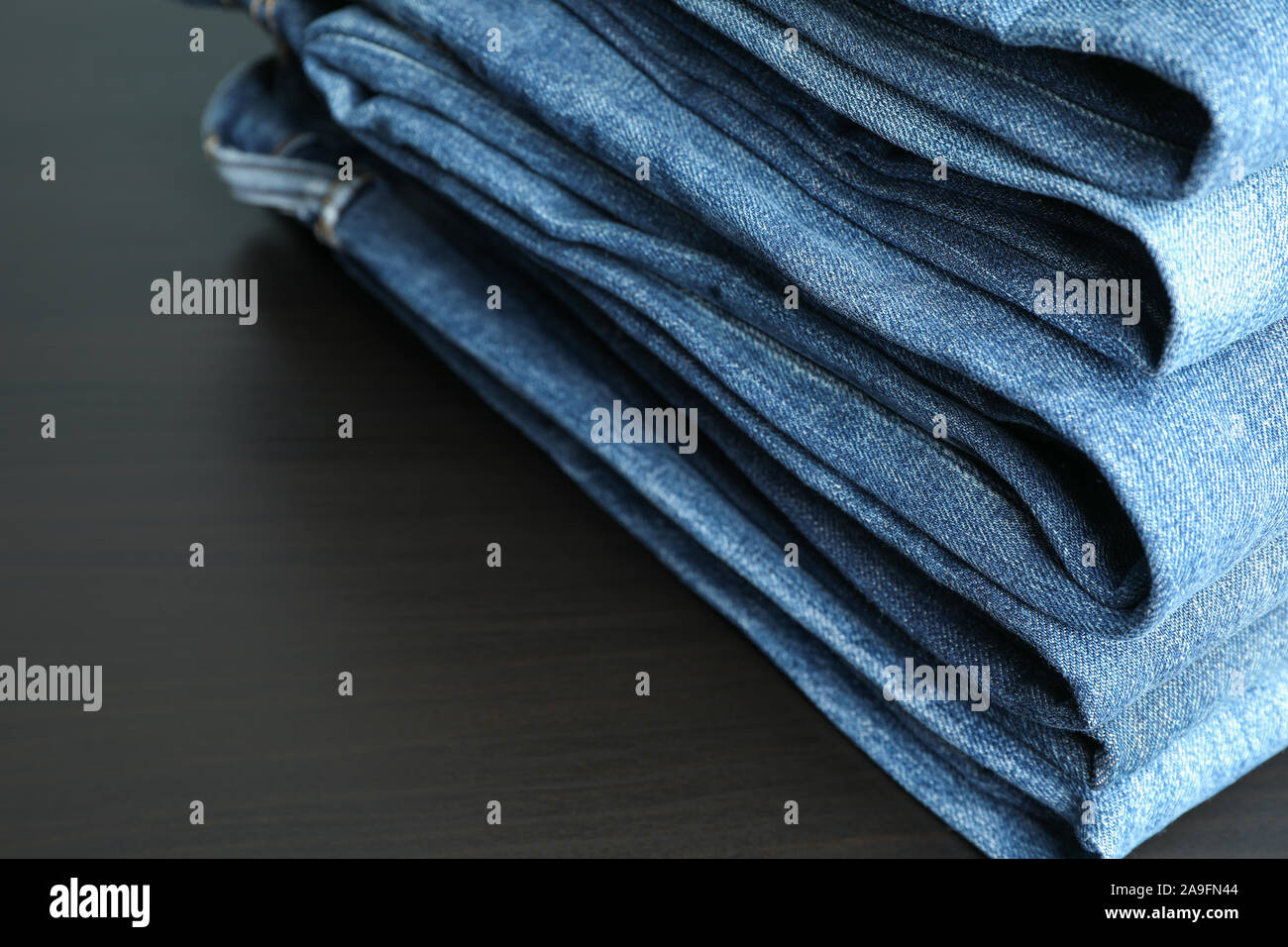 Stack of jeans pants on black table, space for text Stock Photo - Alamy