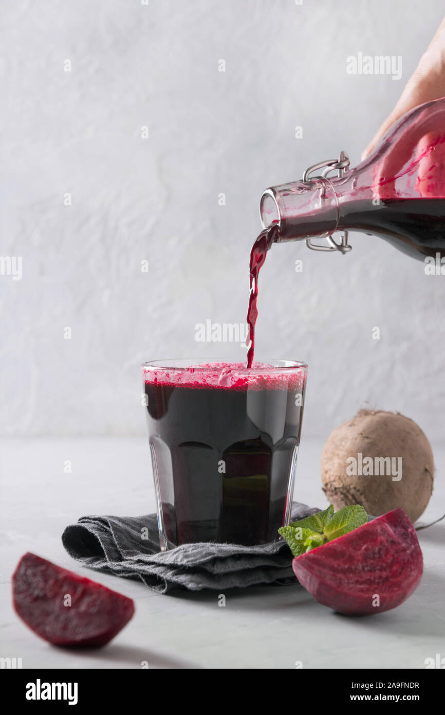 Pouring beetroot juice from bottle to glass. Close up. Vertical ...