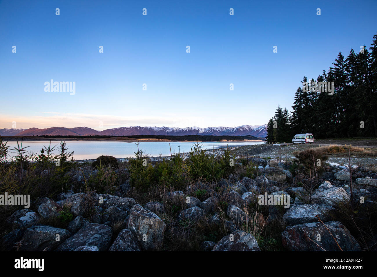 Motorhome parked by blue lake and pine trees at sunrise Stock Photo - Alamy