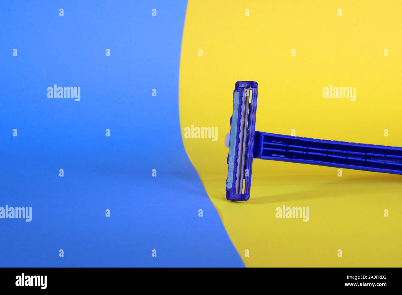 Blue shaving blade on yellow and blue background. Disposable razor for ...