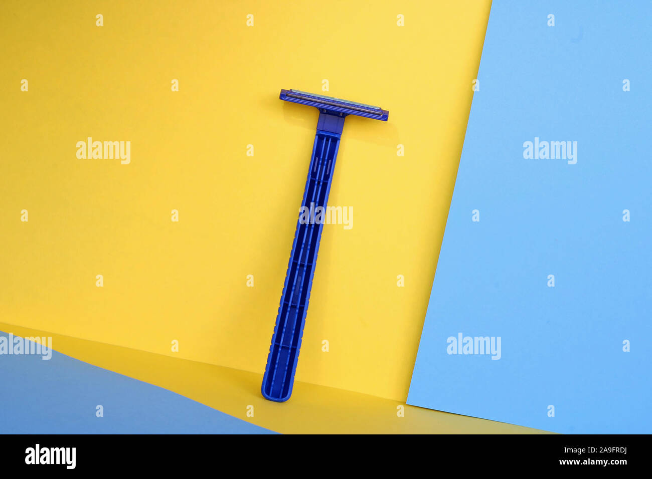 Blue shaving blade on yellow and blue background. Disposable razor for ...