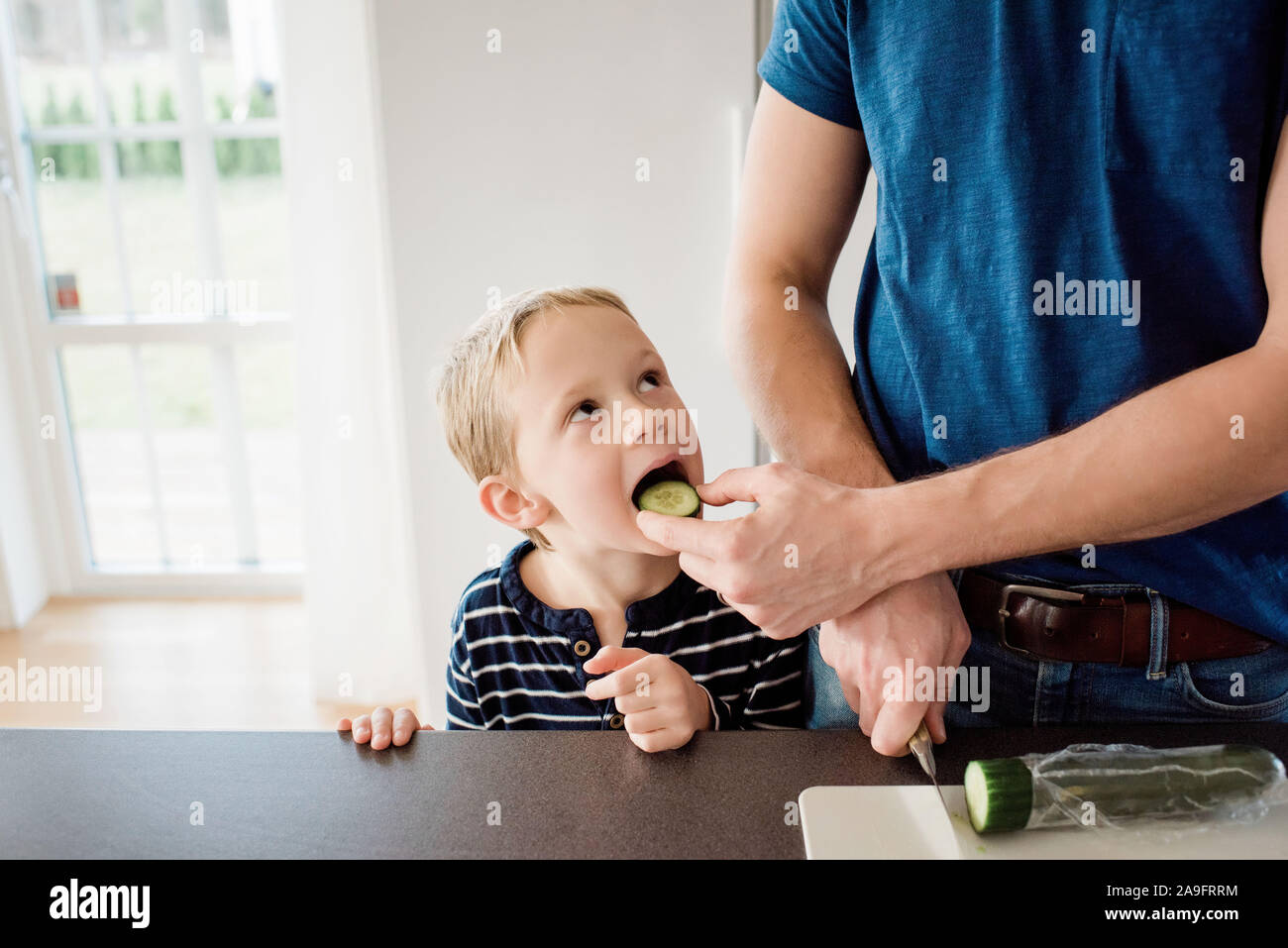 father making his kids packed lunch whilst feeding his son for school ...