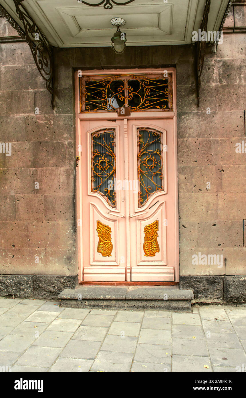 Old milky pink double doors with Windows covered with wrought iron bars ...