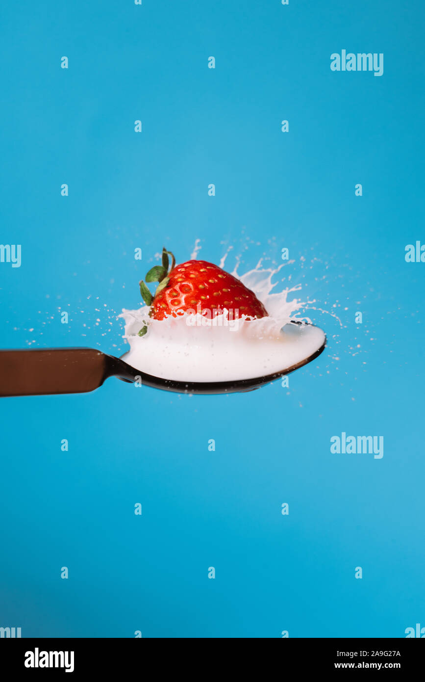 Strawberry falling in spoon with splashing milk Stock Photo - Alamy