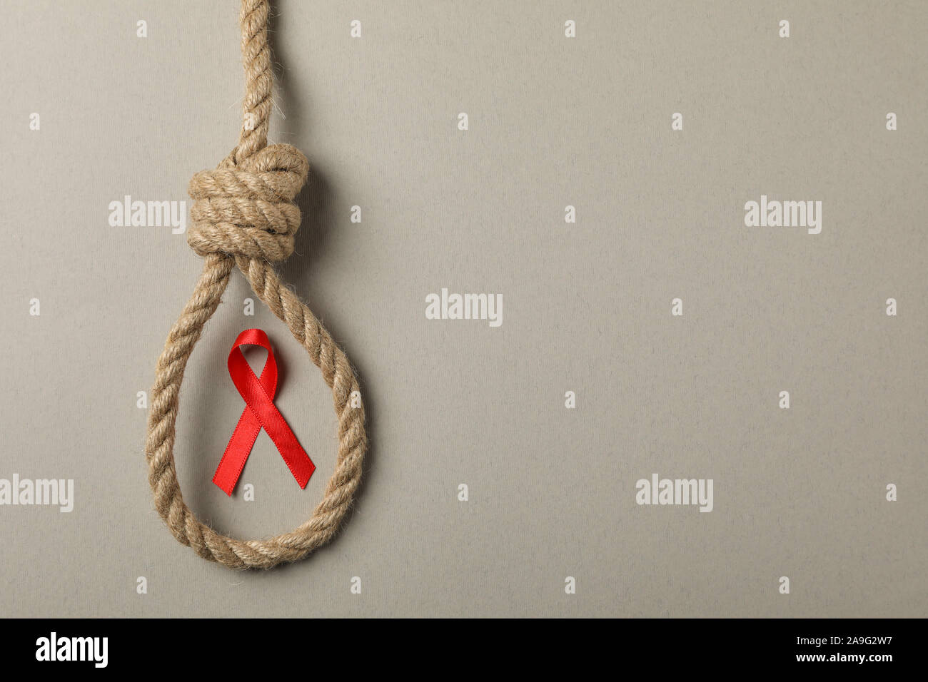 Awareness red ribbon and suicide rope on cardboard background, copy ...