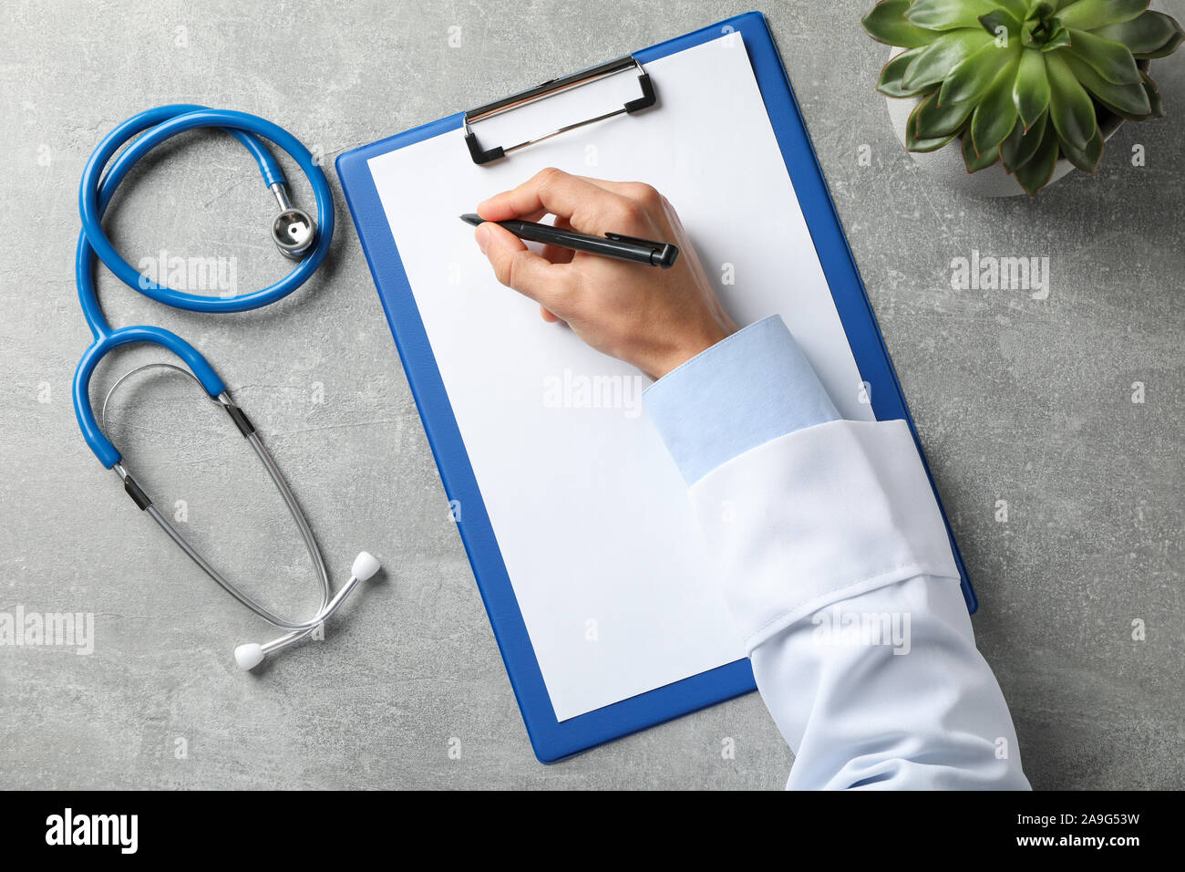 Doctor writing on grey table with stethoscope and plant, top view Stock ...