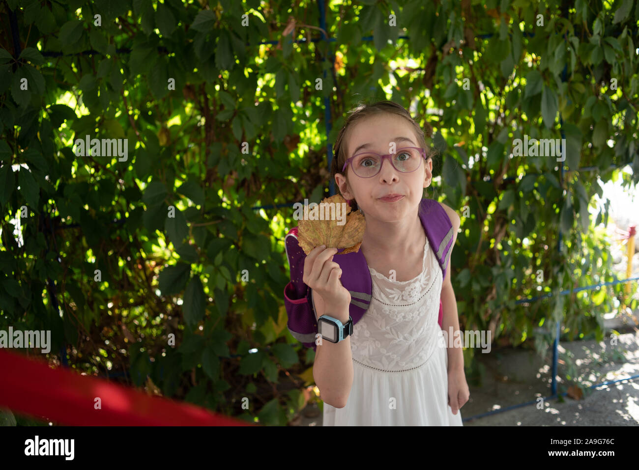 Schoolgirl With A Violet Rucksack And Purple Glasses Girl In A White Dress Wearing Glasses In