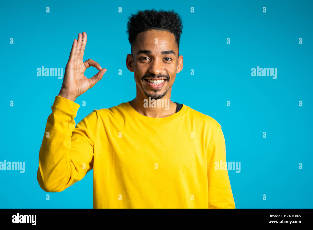 Positive young african guy smiles to camera. Young man making OK sign ...
