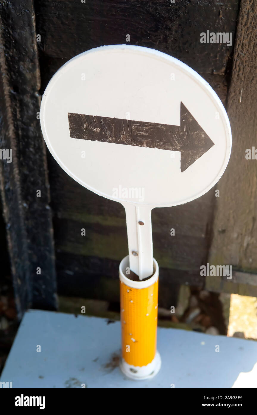 A sign with a big black arrow instructing people which direction to go ...
