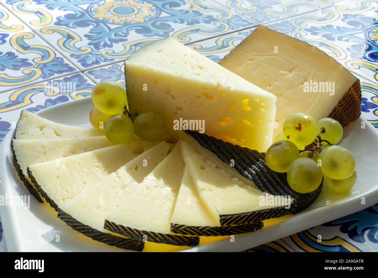 Spanish sheep cheese served with white grapes on andalusian style table ...