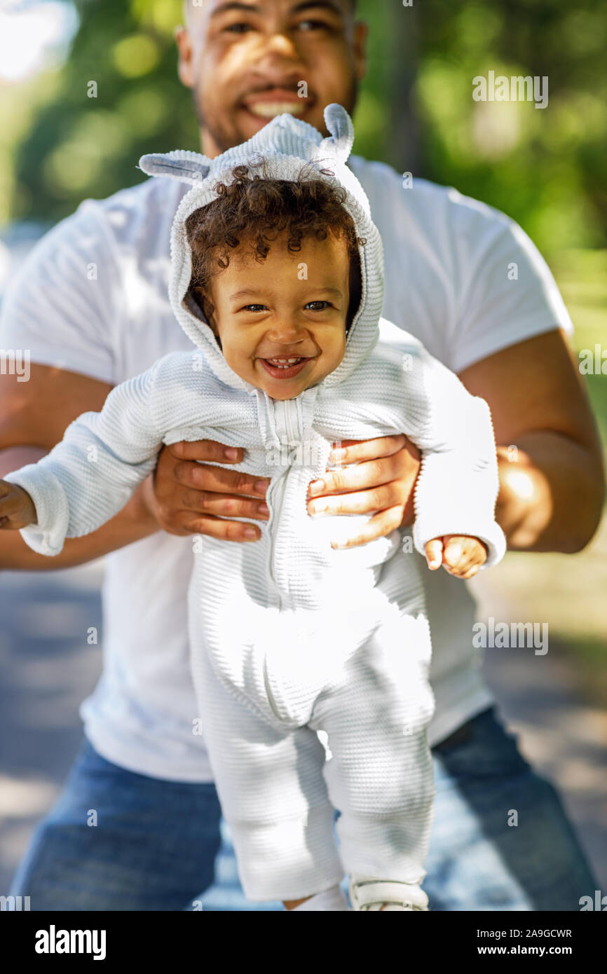 Cute little boy looking at the camera outside while his father holding ...