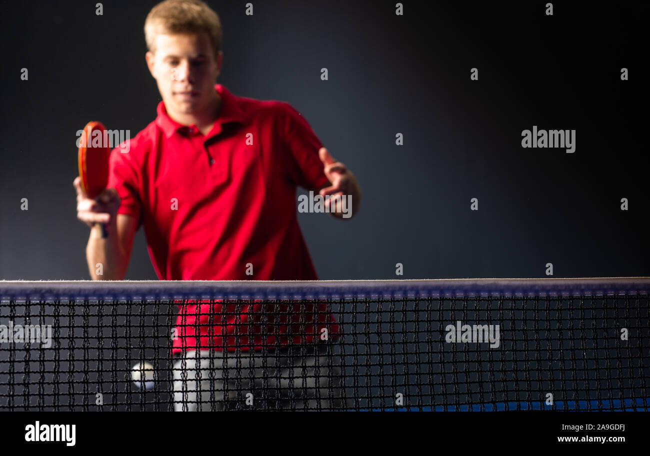 Young man playing table tennis on black studio background Stock Photo ...