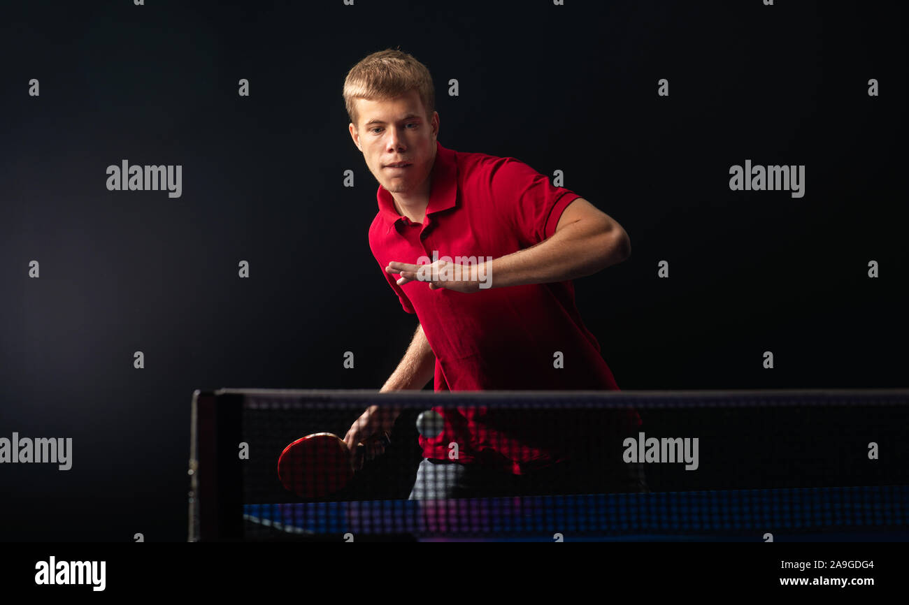 Young man playing table tennis on black studio background Stock Photo ...