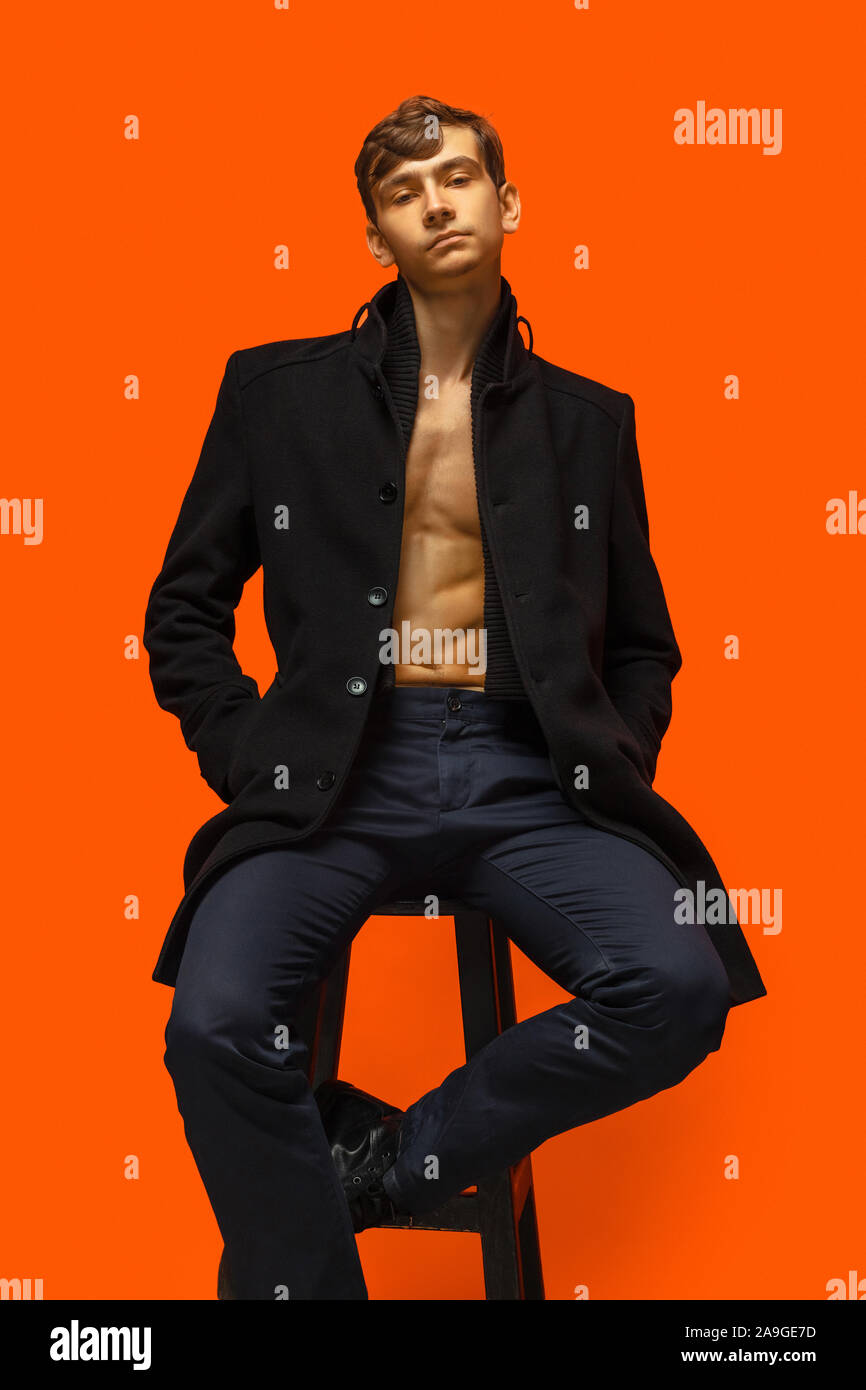 Portrait of a handsome young man isolated on orange studio background ...