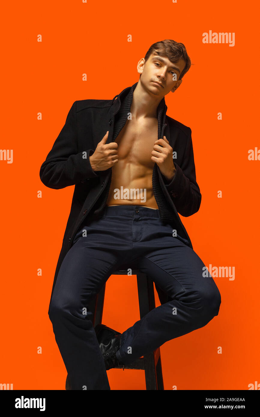 Portrait of a handsome young man isolated on orange studio background ...