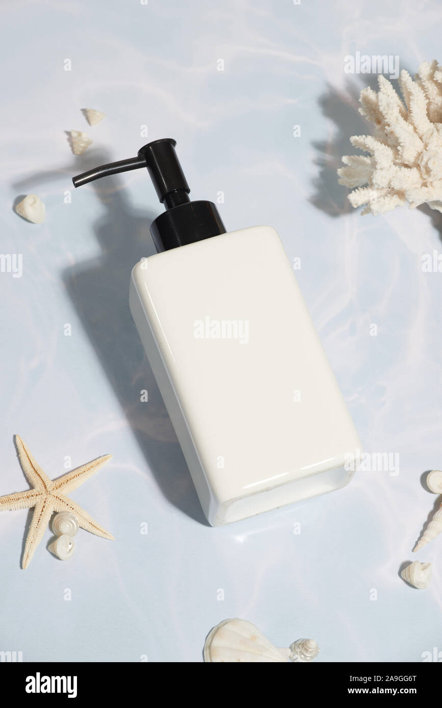 White cosmetic product/ shampoo bottle sea shells on light pastel blue ...