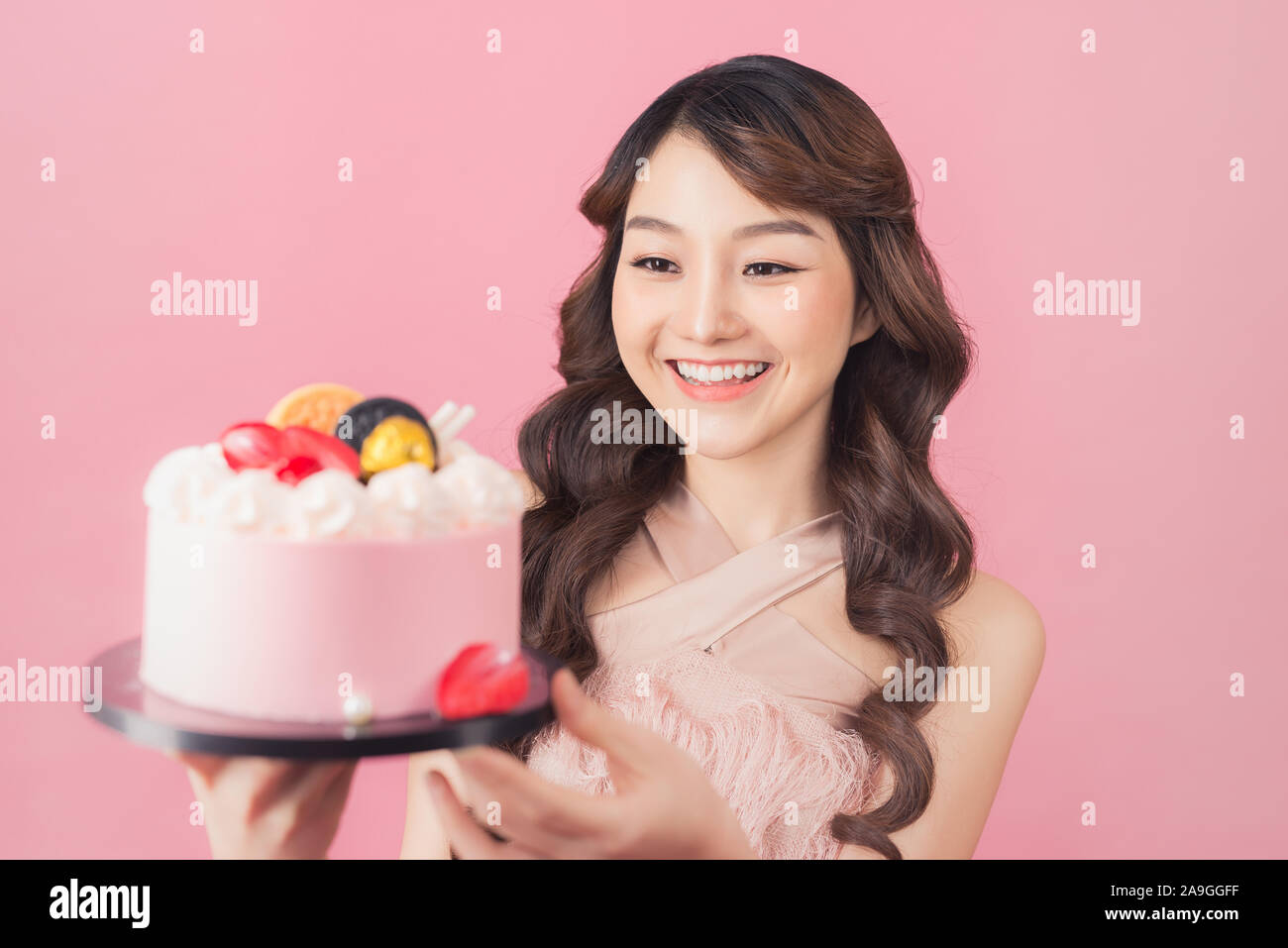 Generous woman holding birthday cake front pink background Stock Photo ...