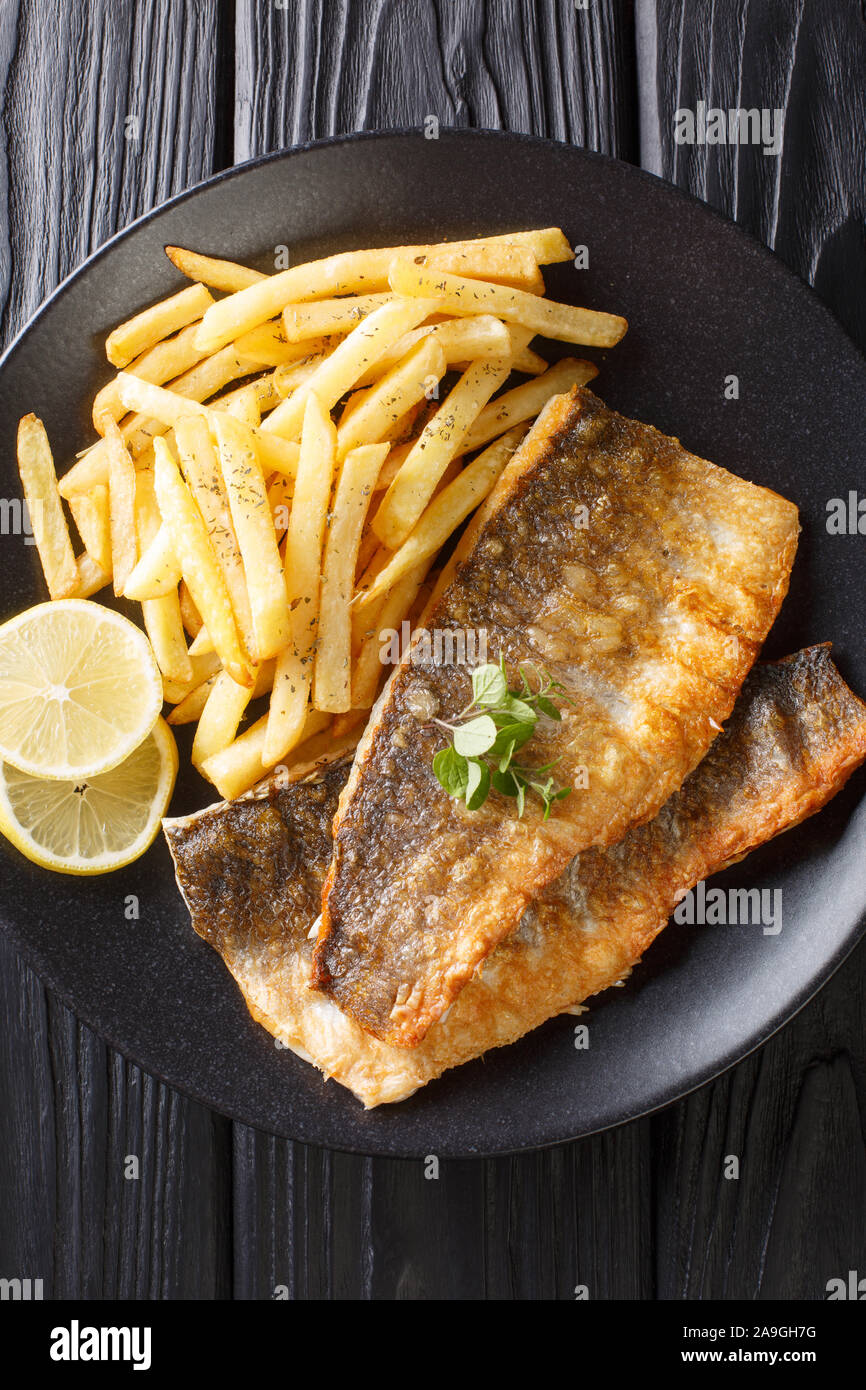 Grilled sea bass fillet with french fries close-up on a plate on the ...