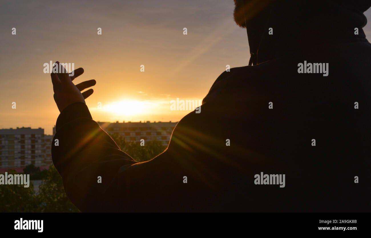 Silhouette of a hooded man preaching at sunrise Stock Photo - Alamy