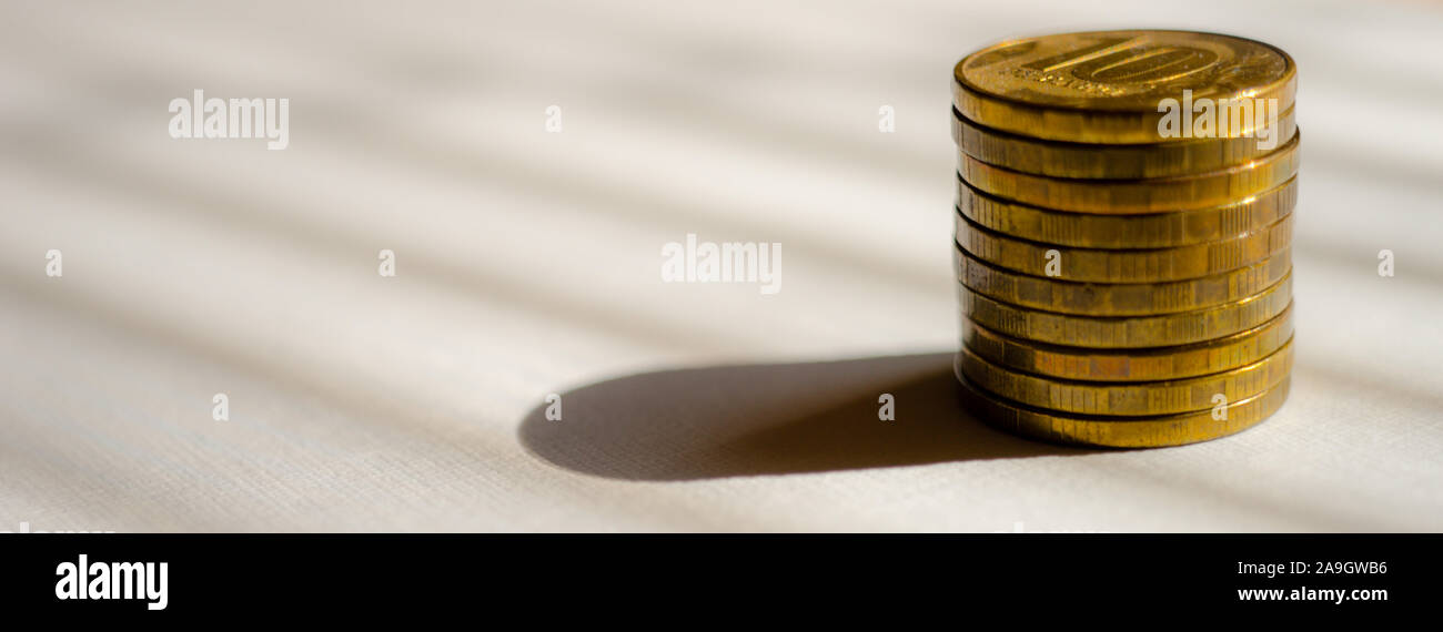 Tower of coins, with hard sunlight and shadows Stock Photo - Alamy