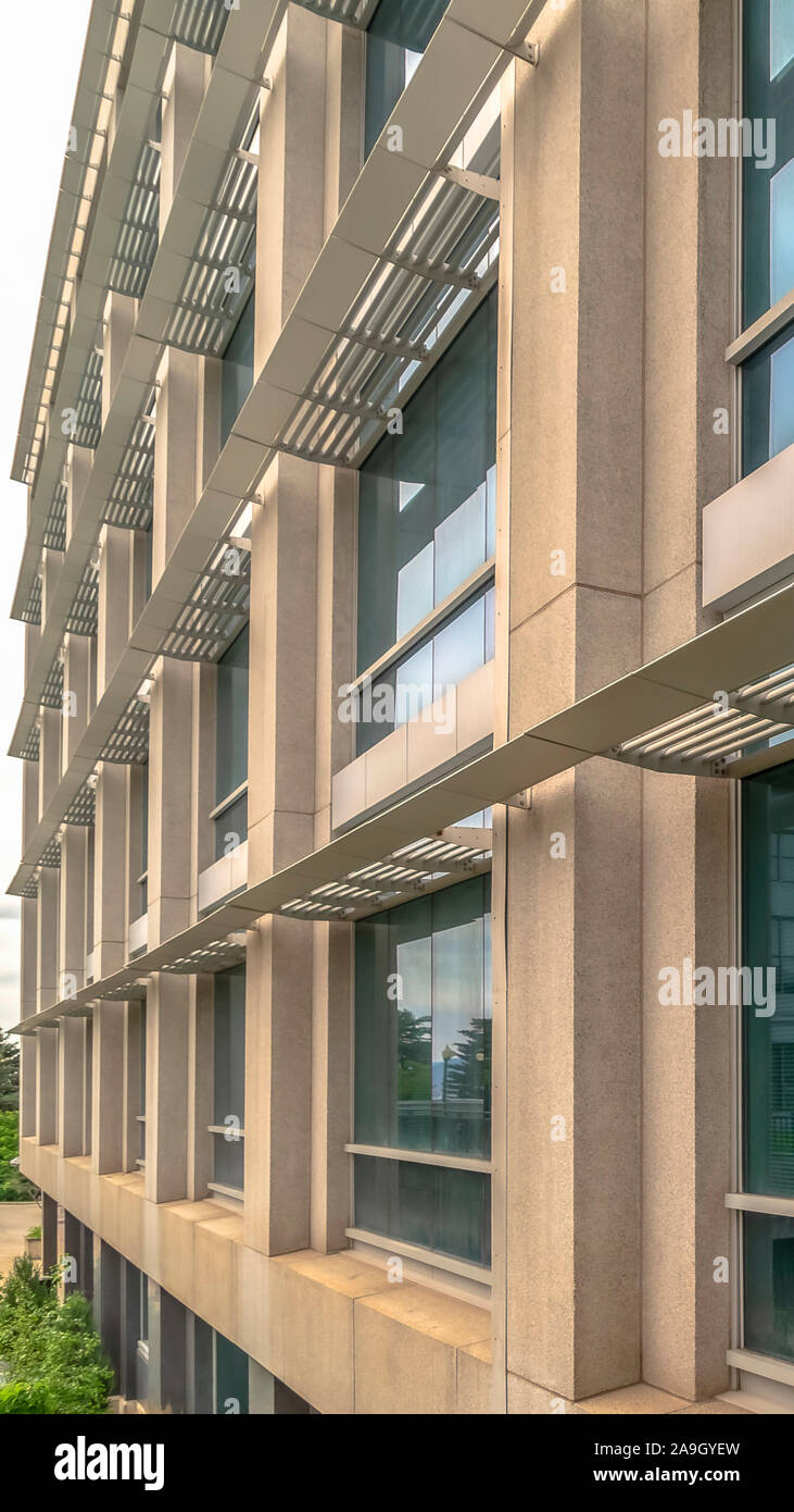 Vertical Close up of the glass windows and concrete exterior wall of a ...