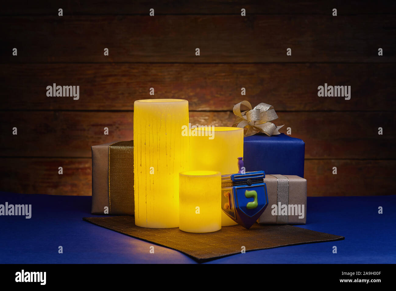 Hanukkah still life of glowing yellow electric candles, wrapped gifts ...