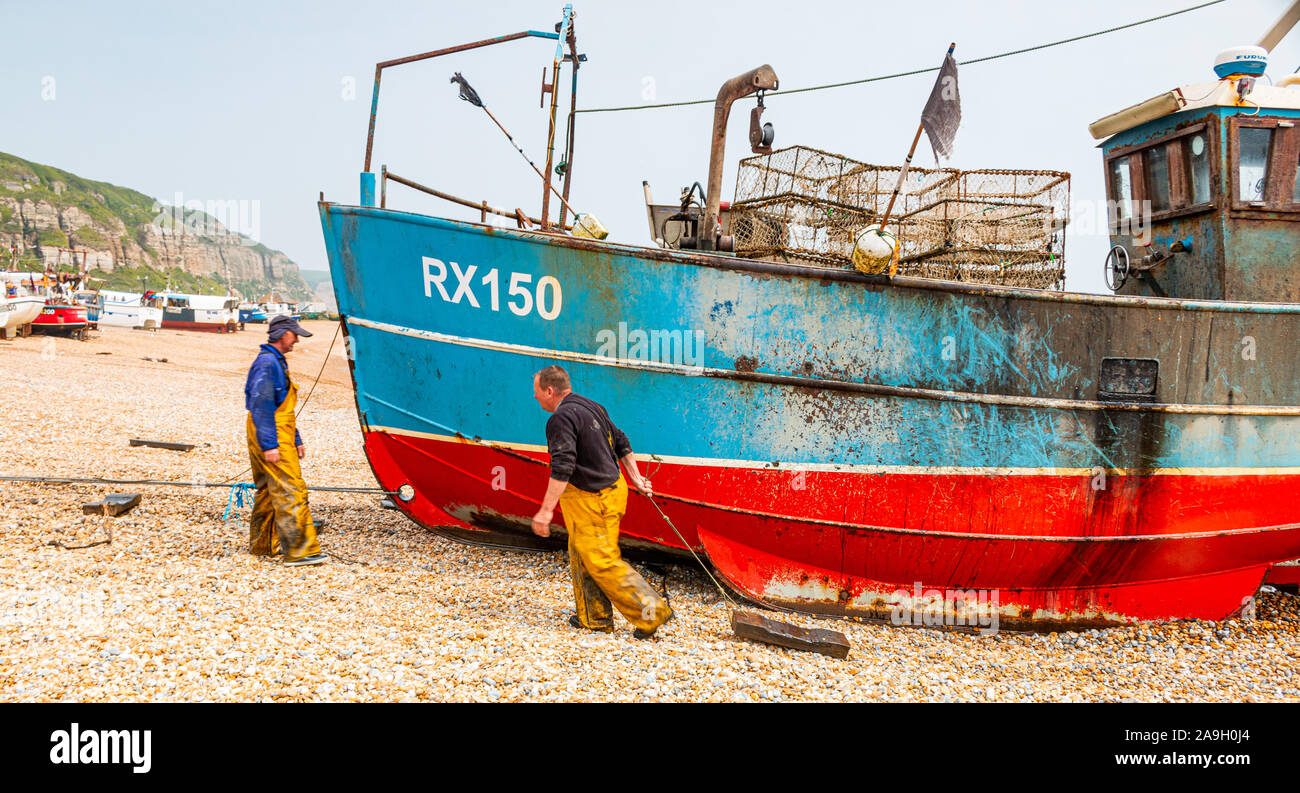 Pulling up the beach fishing boat Stock Photo - Alamy